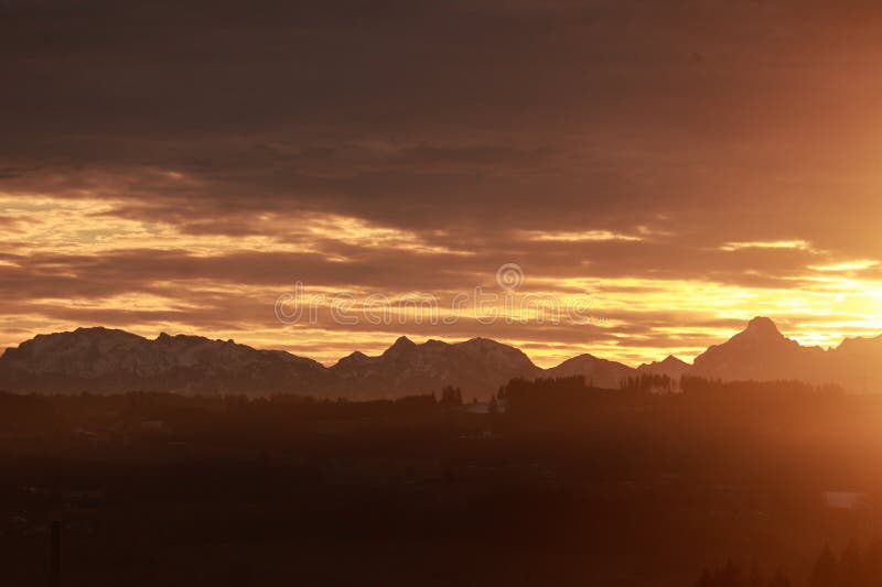 The Sun is Setting Over a Mountain Range, Casting a Warm Glow Over the ...