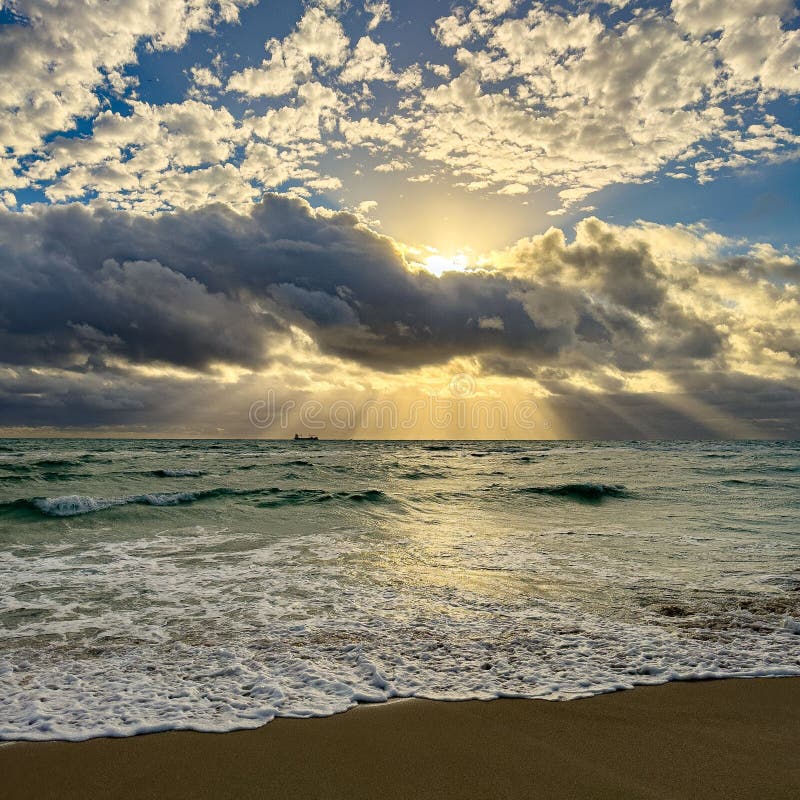 The Sun Setting Over the Ocean on the Beach is Setting on a Cloudy Day ...