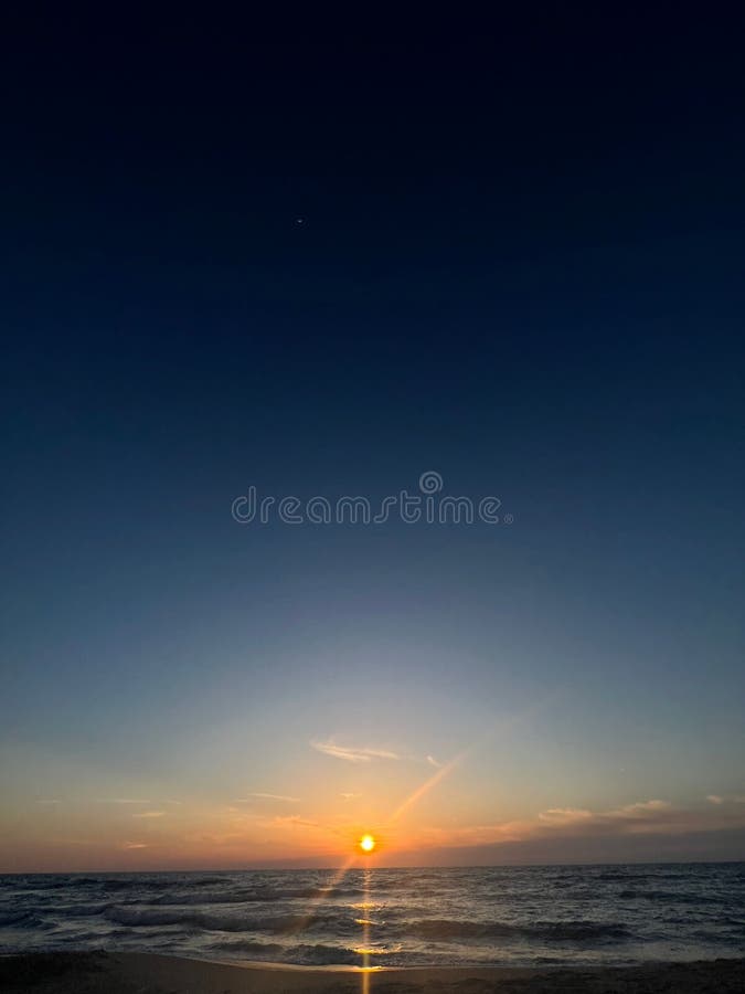 The Sun Setting Over the Ocean on the Beach with Waves Stock Photo ...