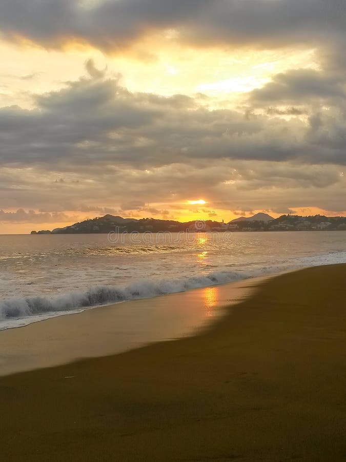 The Sun is Setting Over the Ocean, Casting a Warm Glow Over the Beach ...