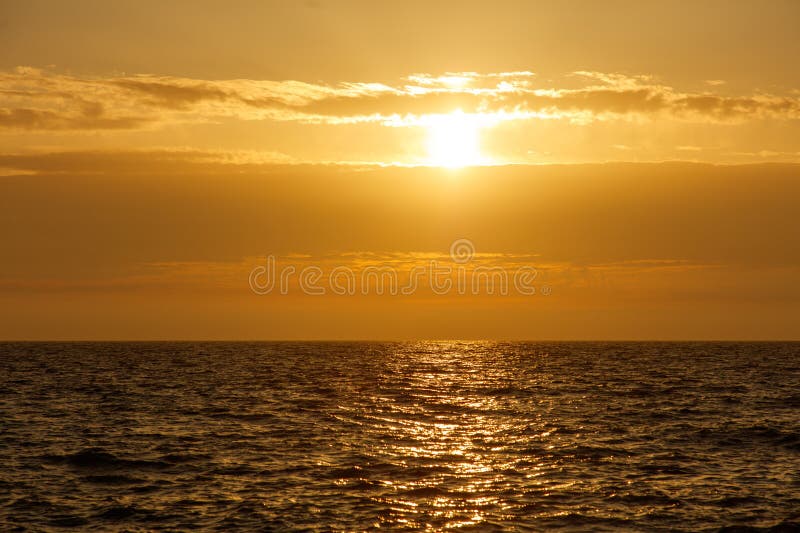 The Sun is Setting Over the Ocean, Casting a Warm Glow on the Water ...