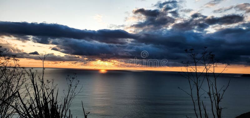 The Sun is Setting Over the Ocean on a Cloudy Day Stock Image - Image ...