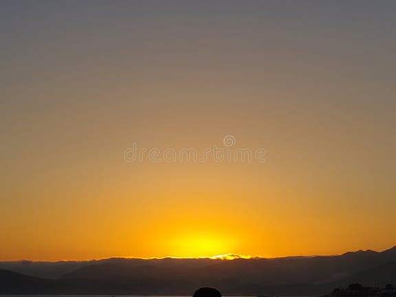 Sun Setting Over the Ocean and Distant Mountains Stock Photo - Image of ...