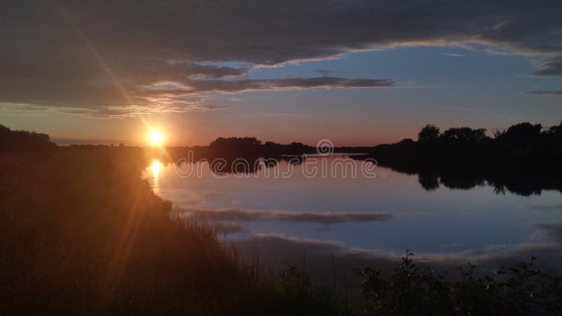 The Sun is Setting Over the River among the Clouds. the Sky and Clouds ...