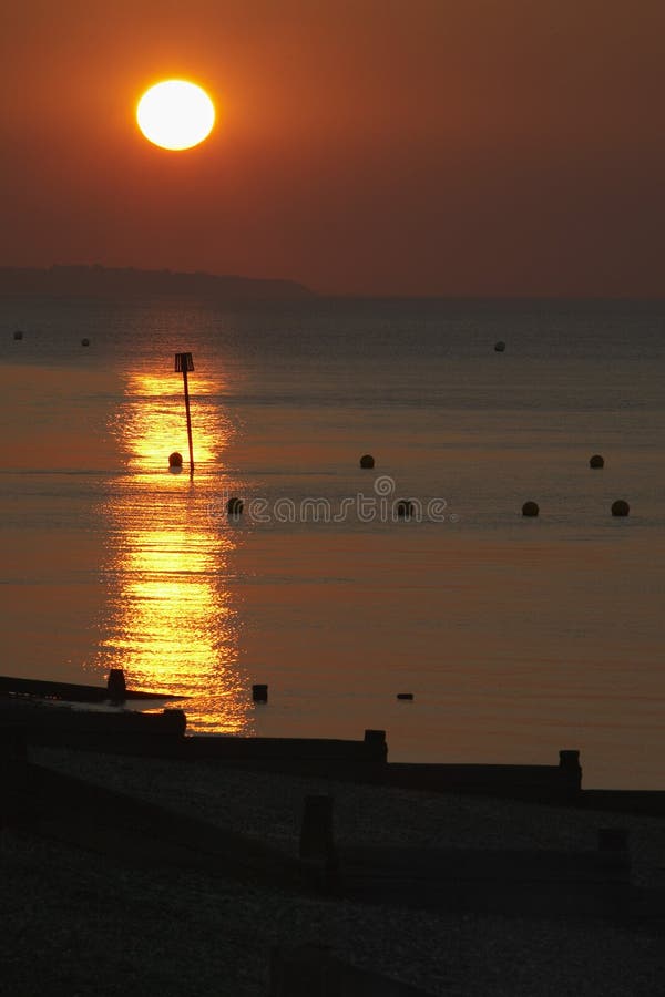 Sun Setting Over Sea and Breakwaters on Beach Stock Image - Image of ...
