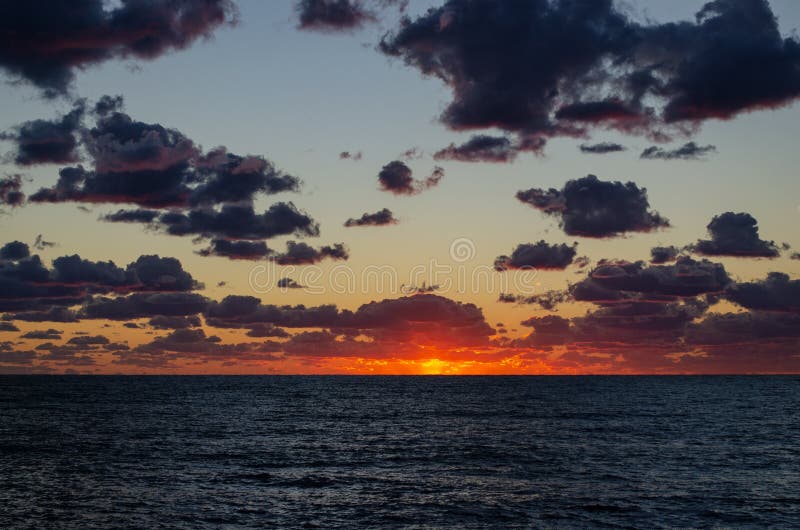 The Red Glow of the Setting Sun Over the Sea with Dark Clouds Stock ...