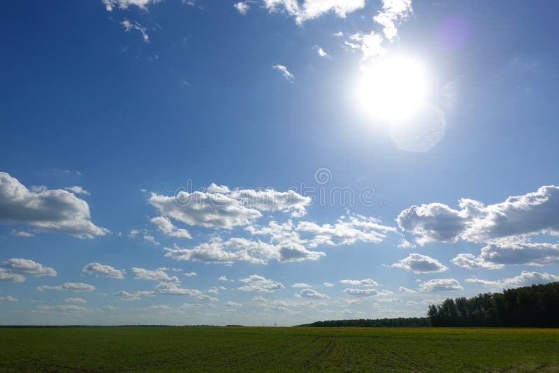 The Sun Shines Over a Grassy Field and Clouds Int he Sky Stock Photo ...