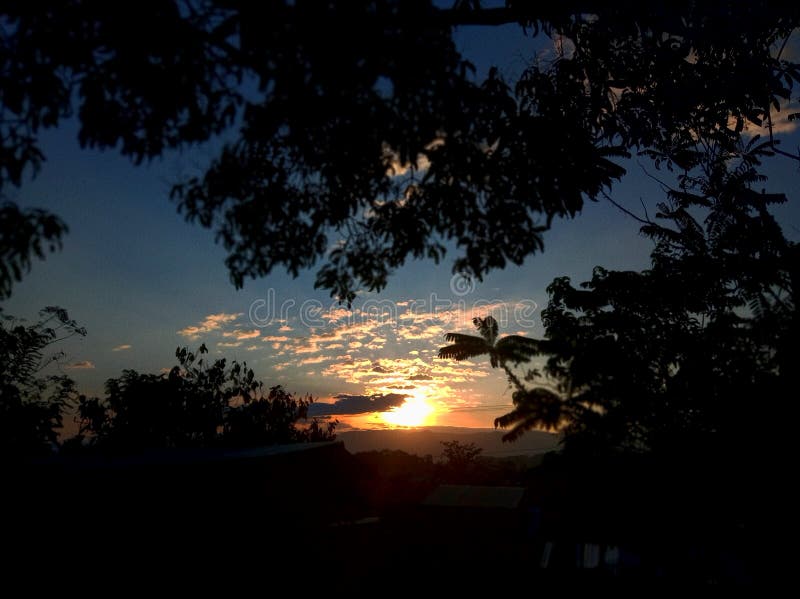 The Sunset Visible Behind the Mountains and Trees Stock Image - Image ...