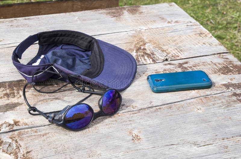 Sunglass, Baseball Cap and Mobile Phone on Table Stock Image - Image of ...