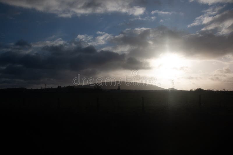 Sunlight Breaking through Dramatic Clouds Over a Dark Rural Landscape in the Evening Stock Image ...