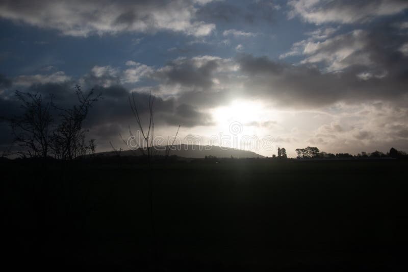 Sunlight Breaking through Dramatic Clouds Over a Dark Rural Landscape ...