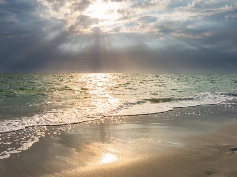Sunlight through Dramatic Clouds Over Ocean and Sand Stock Image ...