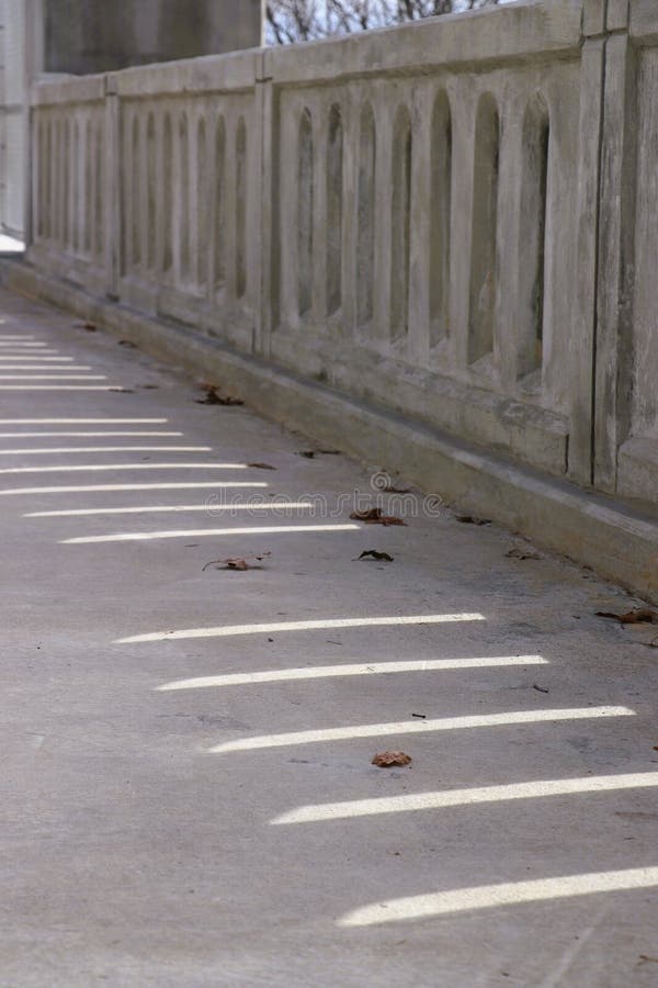 Sunlight on Sidewalk through White Arched Cement Bridge Balustrade with ...