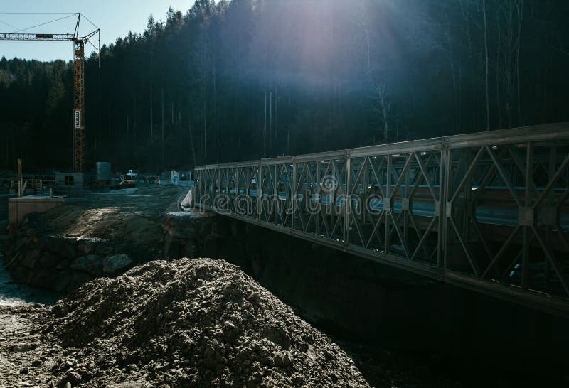 Sunlit Construction Site with Steel Bridge and Forest Background ...
