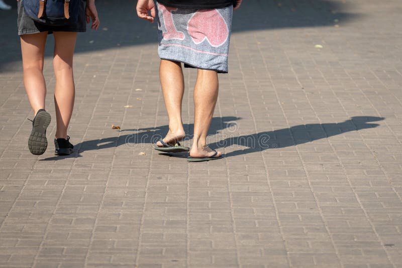 On a Sunny Day, a Couple of People Walk Along the Sidewalk. the Human ...