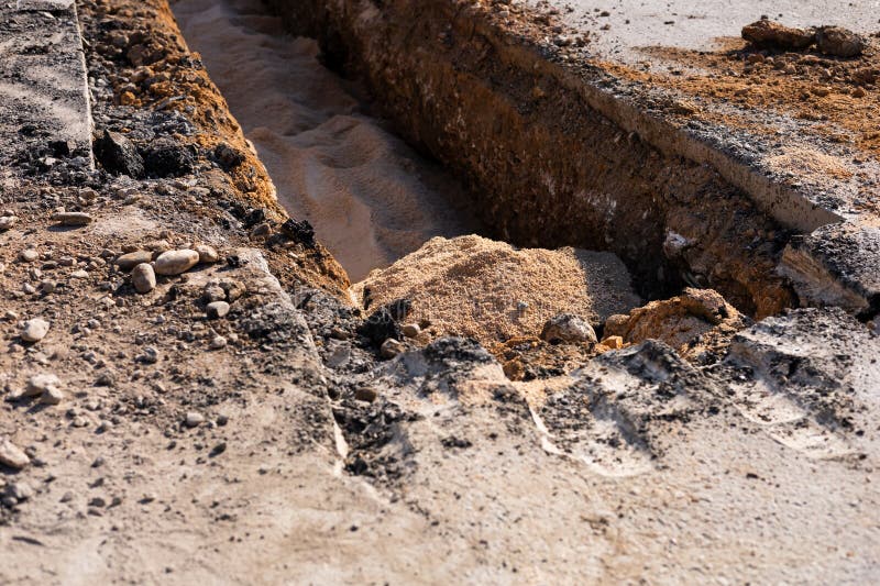 A Sunny Road Construction Site Features a Deep Trench and Scattered ...