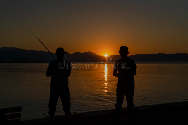 Sunrise on the Horizon with Silhouette of Two Men Catching Fish at ...