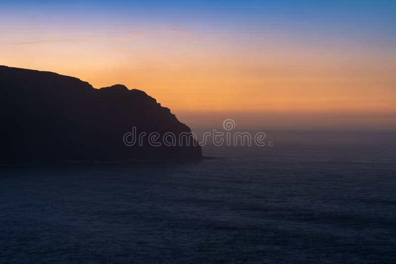 Sunrise Over the Ocean with Cliff in Silhouette and Beautiful Colors ...