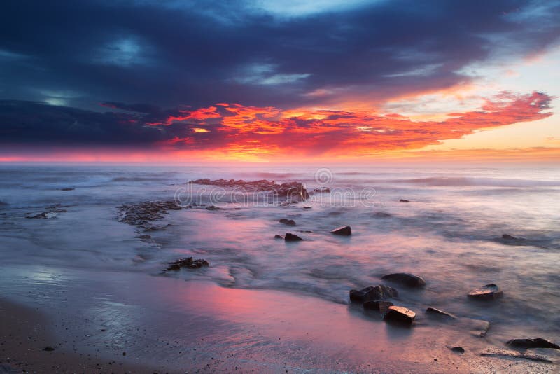 Sunrise Over the Ocean with Rocks and Water in Foreground Stock Photo ...