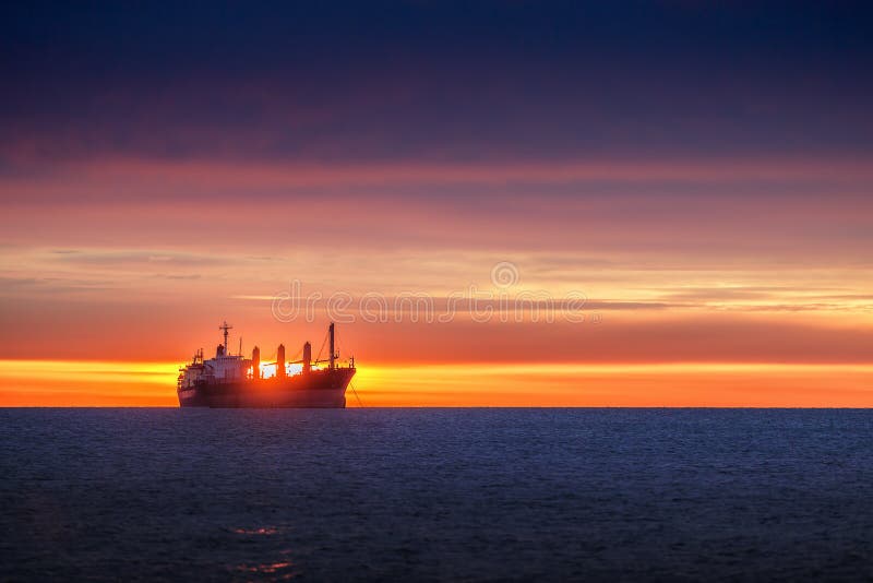A Cargo Ship Sailing On The Horizon At The Sunrise Stock Image - Image ...