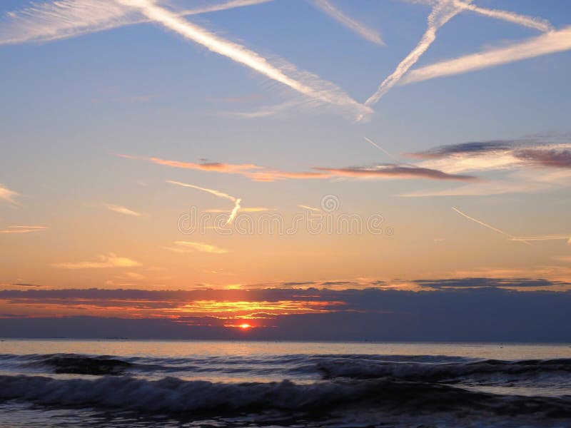 The Sun Setting Behind the Clouds in the Sea Stock Image - Image of ...