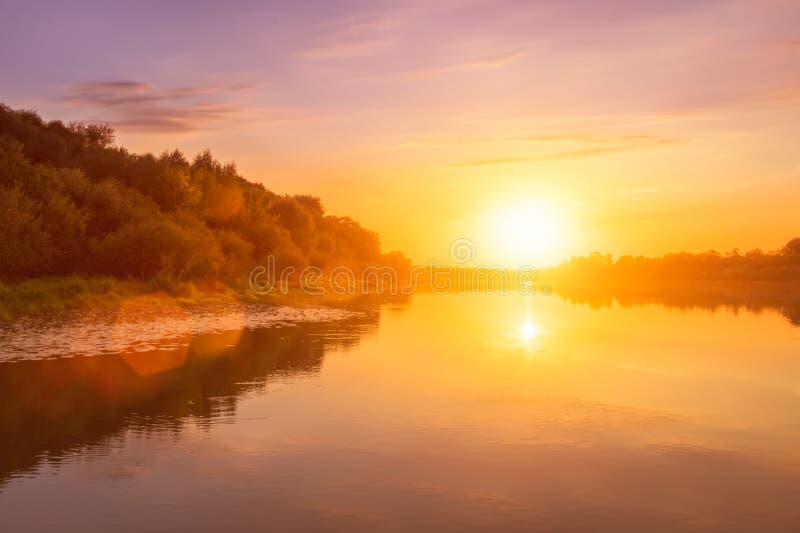 Sunset or Dawn on a River with a Cloudy Sky and Sun Rays Reflected in ...