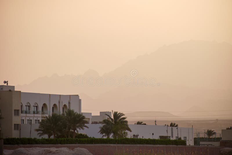 Sunset Landscape with Remote Hotel Complex Against Dark Mountain Peaks ...