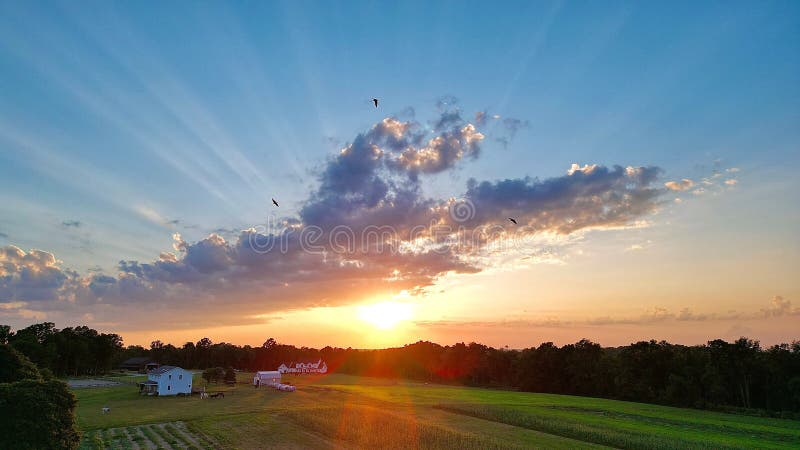 Sunset with Light Rays through the Clouds Over a Field in West ...