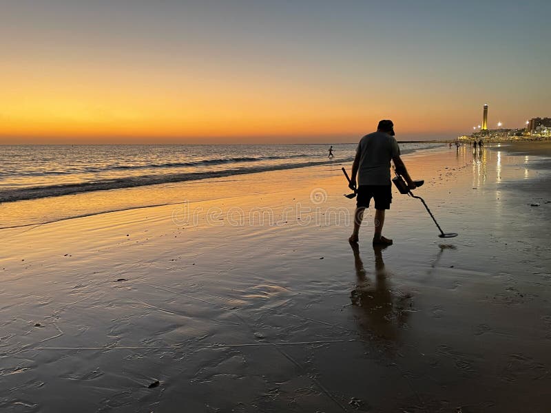 Sunset with Man with Metal Detector on Sandy Beach Stock Photo - Image ...