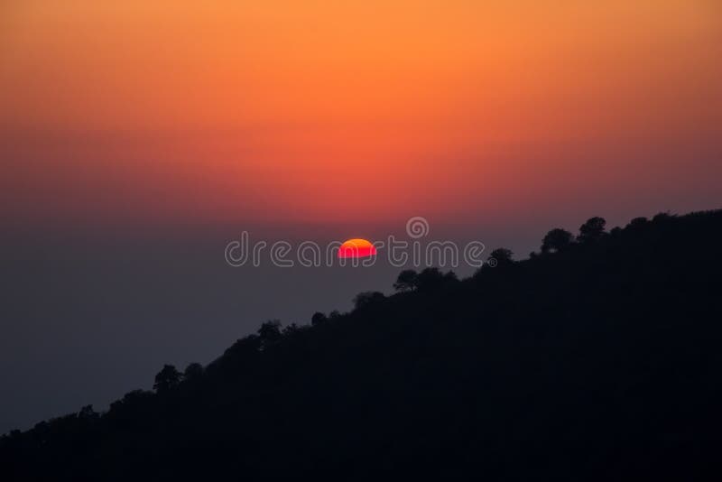 Sunset in the Mountains. Red Sun Goes Down in a Haze of Clouds Stock ...
