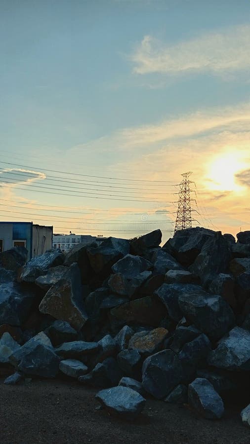 Sunset Over a Construction Site with a Pile of Rocks in the Foreground ...