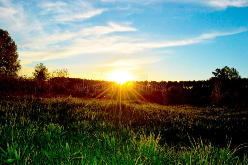 A Sunset Over a Grass Field Stock Photo - Image of lighting, cloud ...