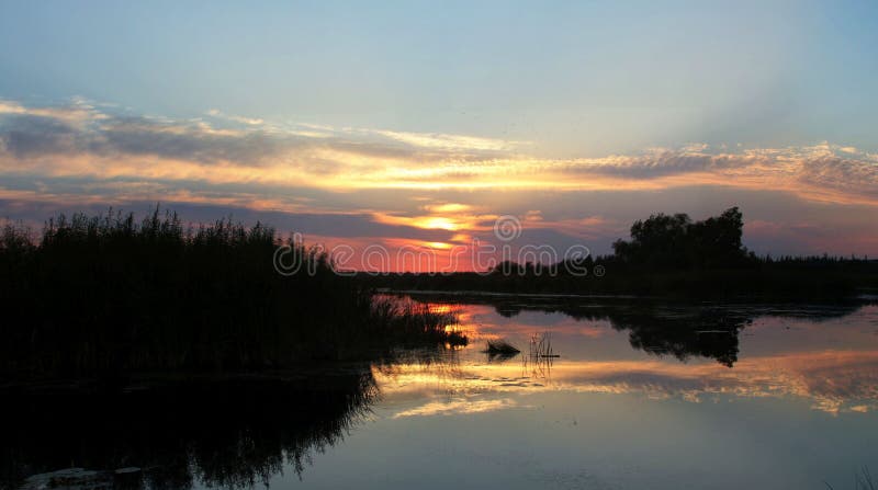 Sunset Over the Marsh Lake Beind Clouds Stock Photo - Image of ...