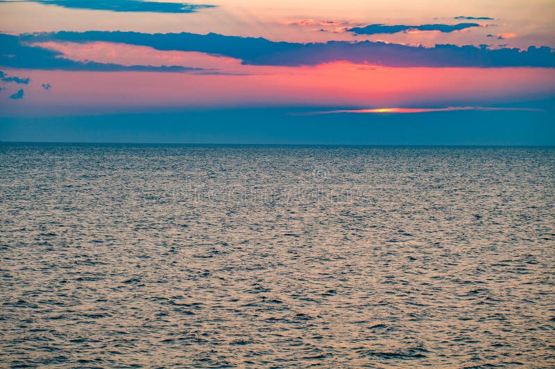Sunset Over Water Surface of Sea and Red Sun in Clouds Above Horizon ...