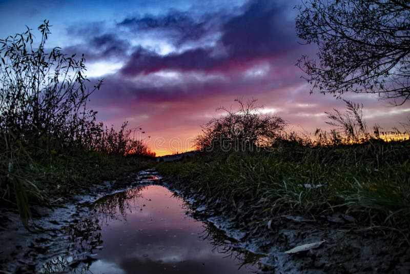 The Sunset is Reflected in a Puddle of a Road Stock Image - Image of ...