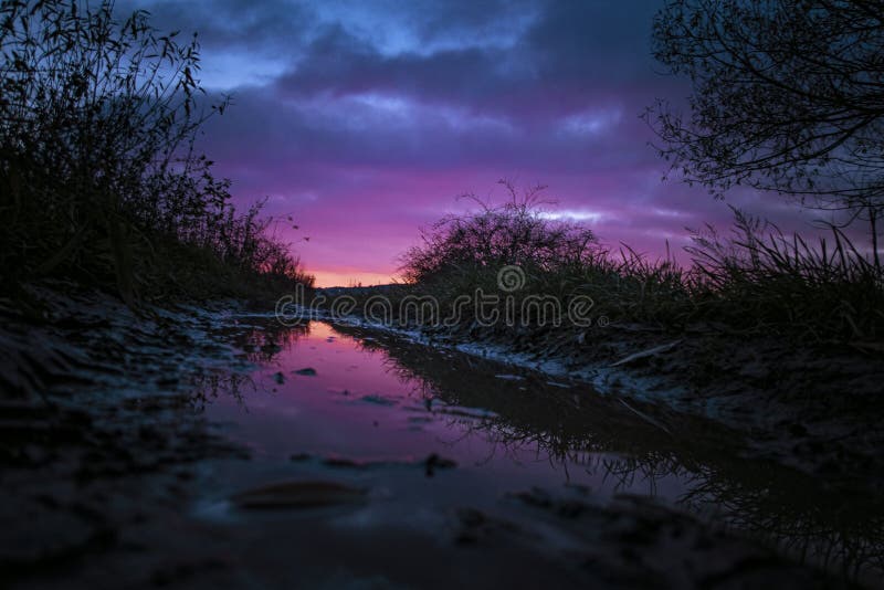 The Sunset is Reflected in a Puddle of a Road Stock Photo - Image of ...