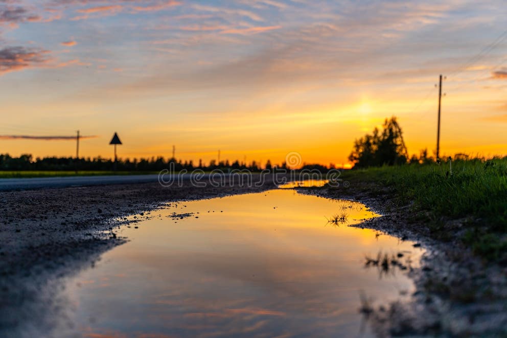 Sunset Reflection in Puddle on Side of Road Stock Photo - Image of ...