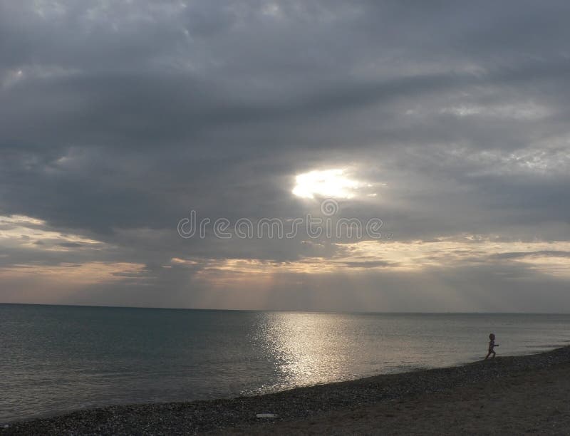Sunset on Sea with Grey Cloudy Sky, Running Boy, Rays of Light Stock ...