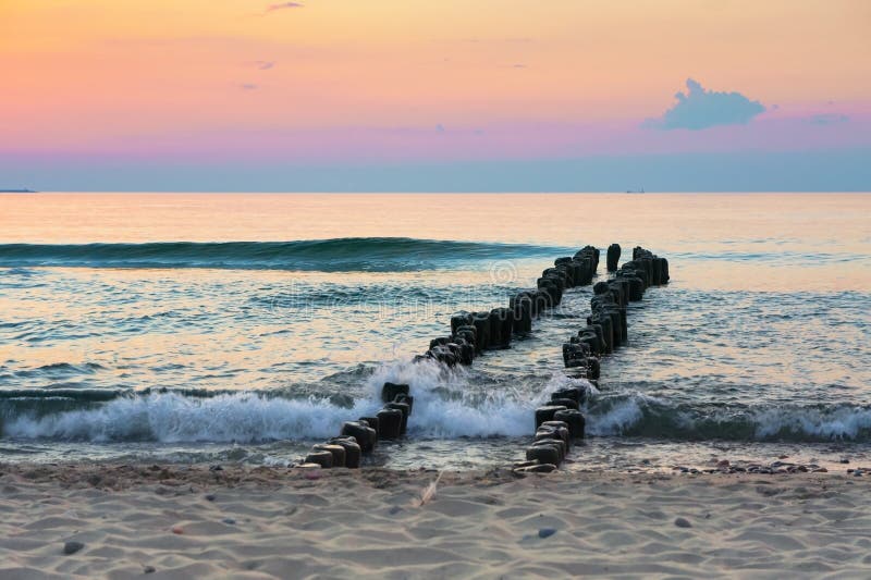 Sunset on the Seashore, Breakwaters in the Sea at Sunrise Stock Photo ...