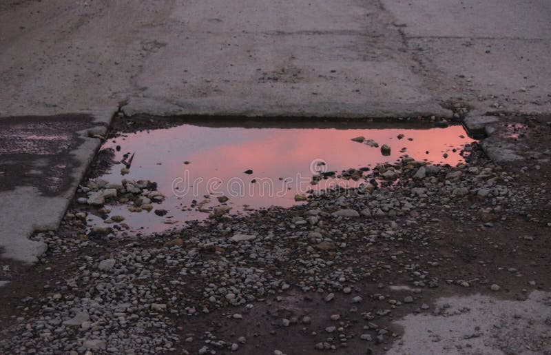 Sunset Sky with Clouds Reflected in a Puddle on a Road of Concrete ...