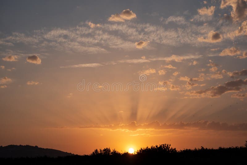 Sunset with Sun almost Hidden and Shadows on the Clouds and Blue Sky ...