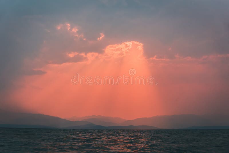 Sunset with Sunbeams Over Ocean with Mountain in Distance. Stock Photo ...