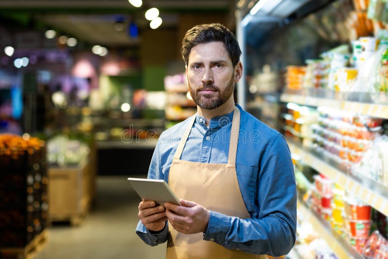 Supermarket Worker Using Tablet in Grocery Store with Focused ...