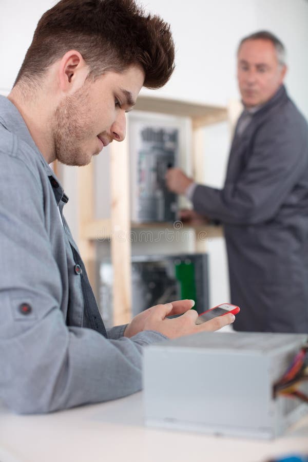 Supervisor Spots Apprentice Using Smartphone at Work Stock Image ...