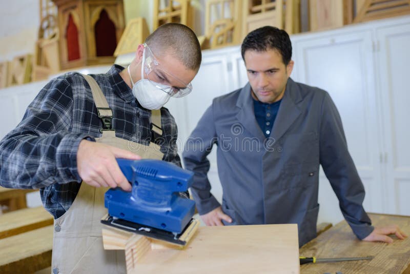 Supervisor Watching Apprentice Carpenter Use Sander Stock Image - Image ...
