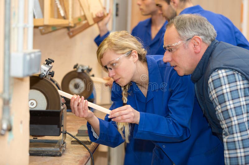 Supervisor Watching Female Apprentice Carpenter Use Grinding Wheel ...