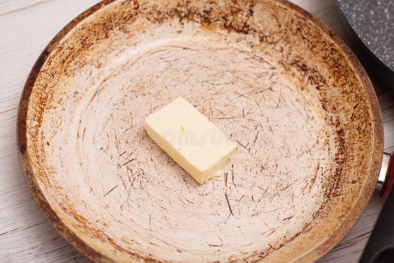 The Surface of a Damaged Frying Pan Coating with a Piece of Butter ...