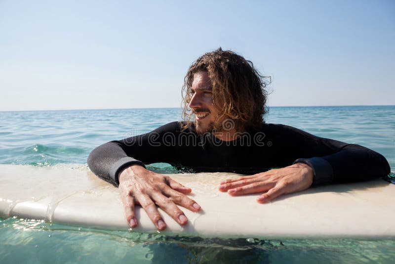 Surfer Leaning on Surfboard in Sea Stock Image - Image of smiling ...