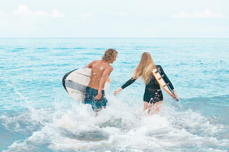 Surfers At The Beach Smiling Couple Of Surfers Walking On The Beach