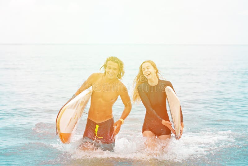 Surfers At The Beach Smiling Couple Of Surfers Walking On The Beach
